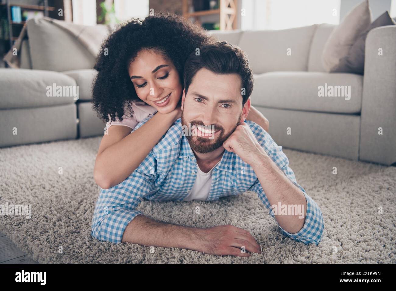 Portrait of two young nice partners cuddle lay floor modern interior ...