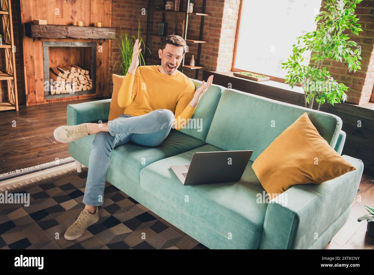 Full length photo of young guy sit couch video call netbook excited ...