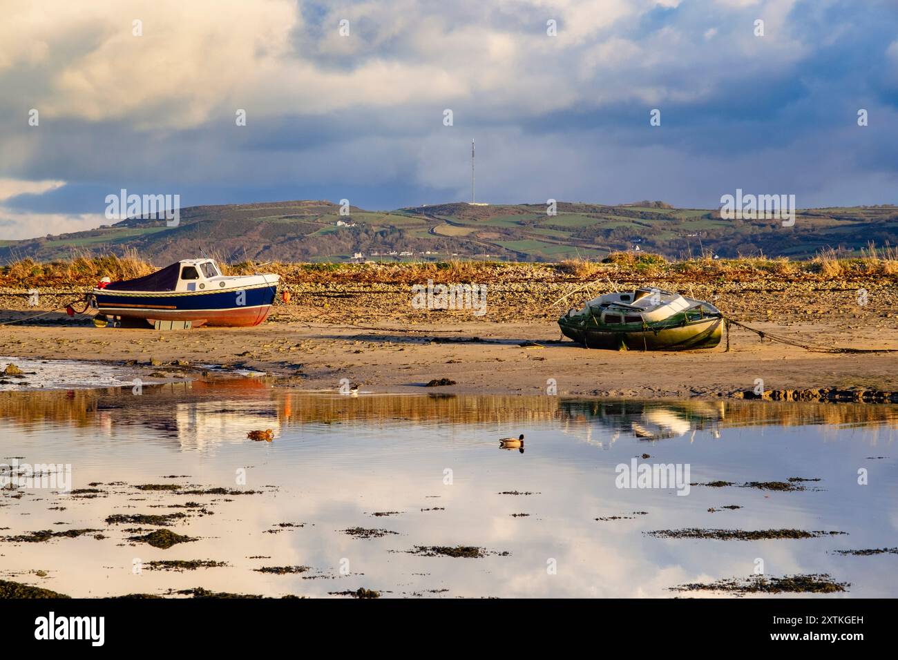 Grounded boats on sandbank with incoming tide in harbour at Red Wharf ...