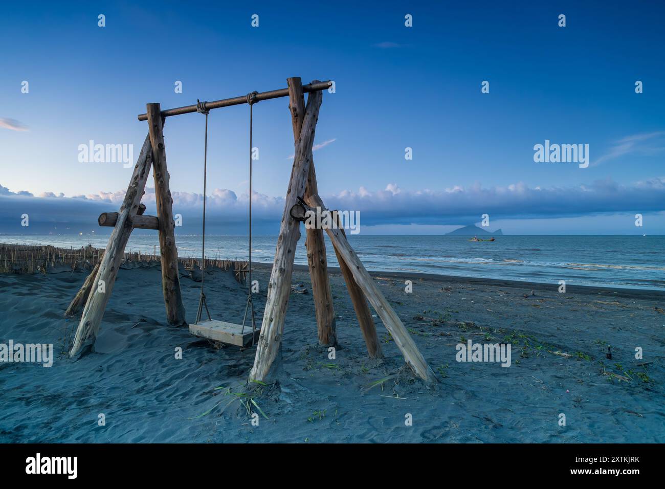A solitary wooden swing set beckons on a tranquil beach. In the ...