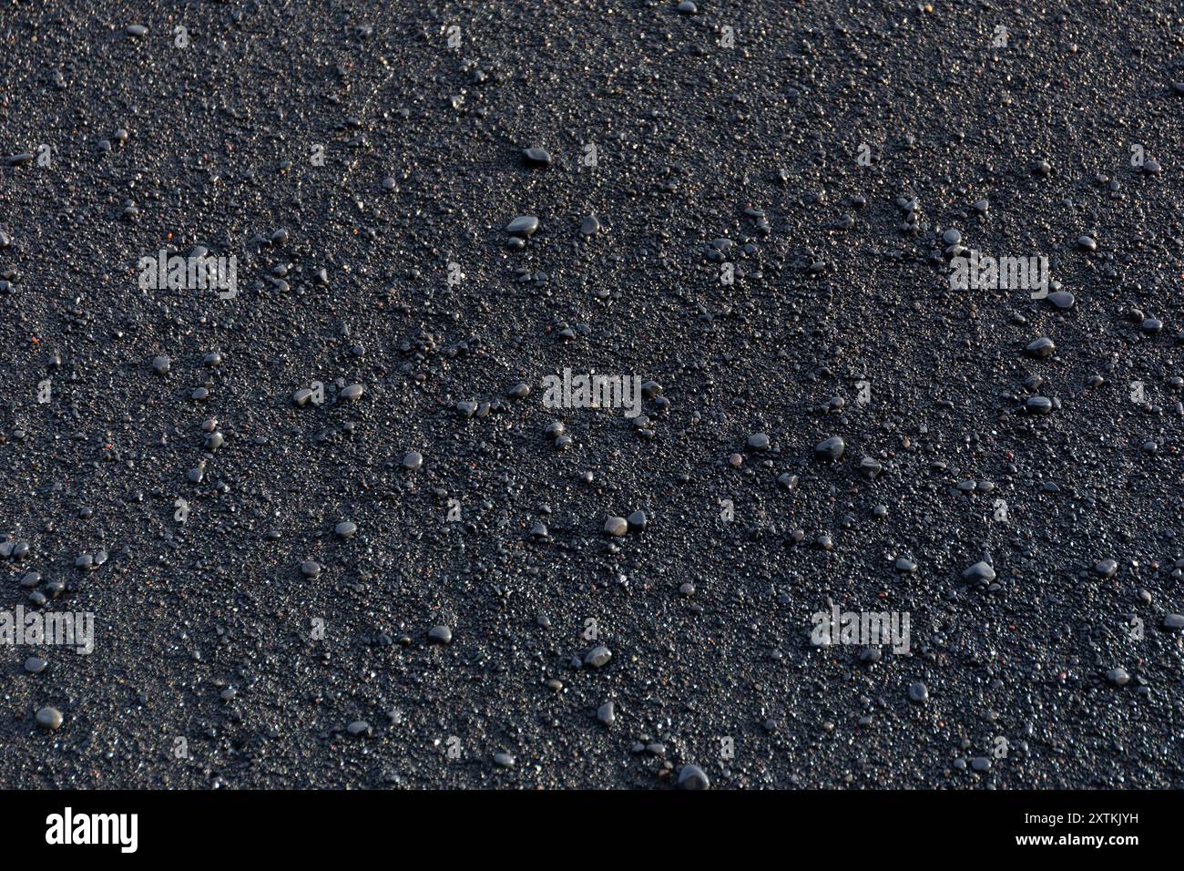 Black volcanic sand beach with shiny volcanic stones background on ...