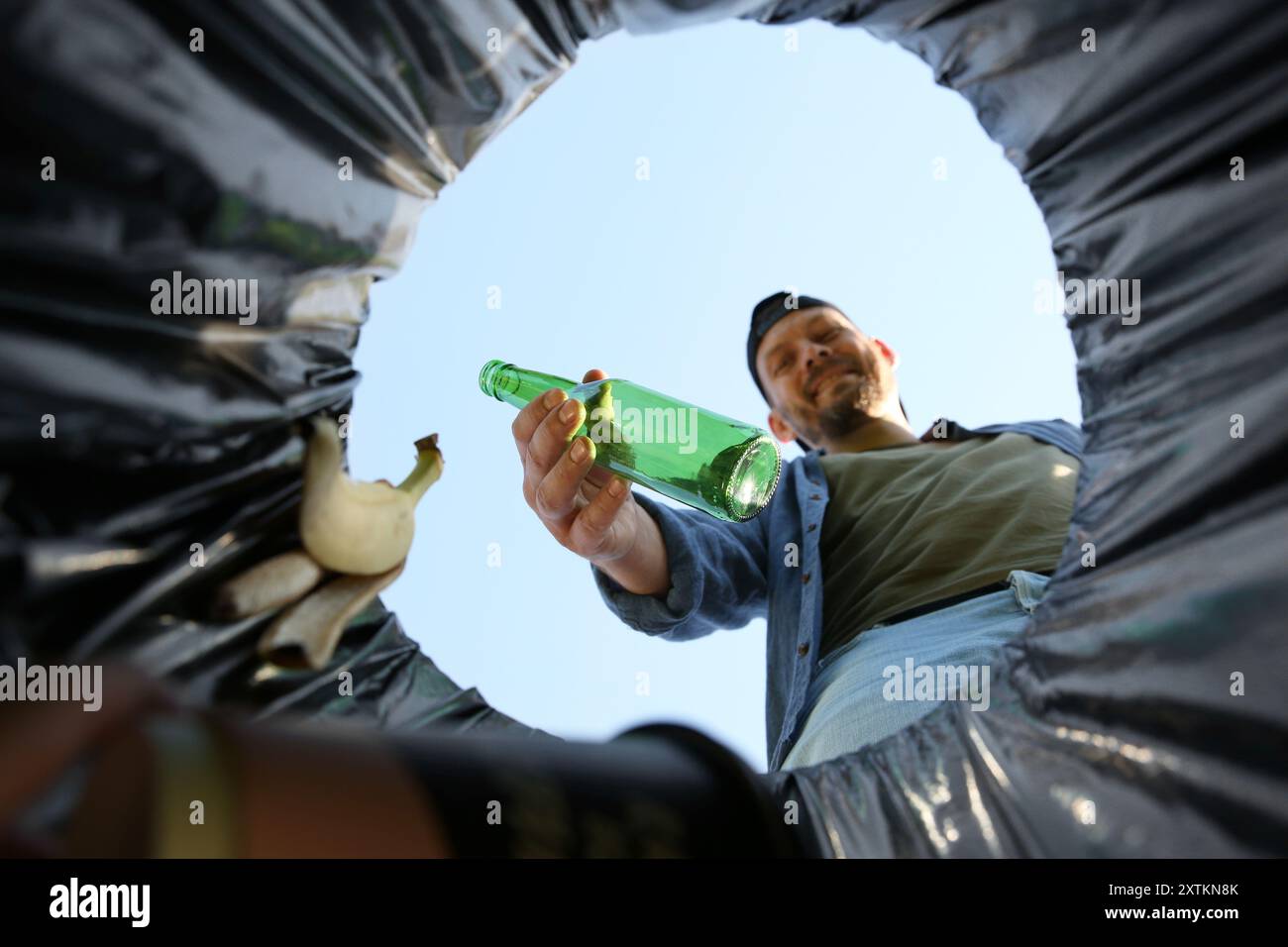 Man throwing glass bottle into garbage bin outdoors, bottom view Stock ...