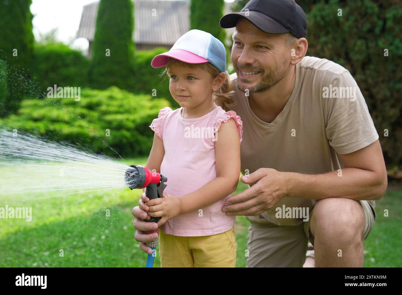 Father and his daughter watering lawn with hose in backyard Stock Photo ...
