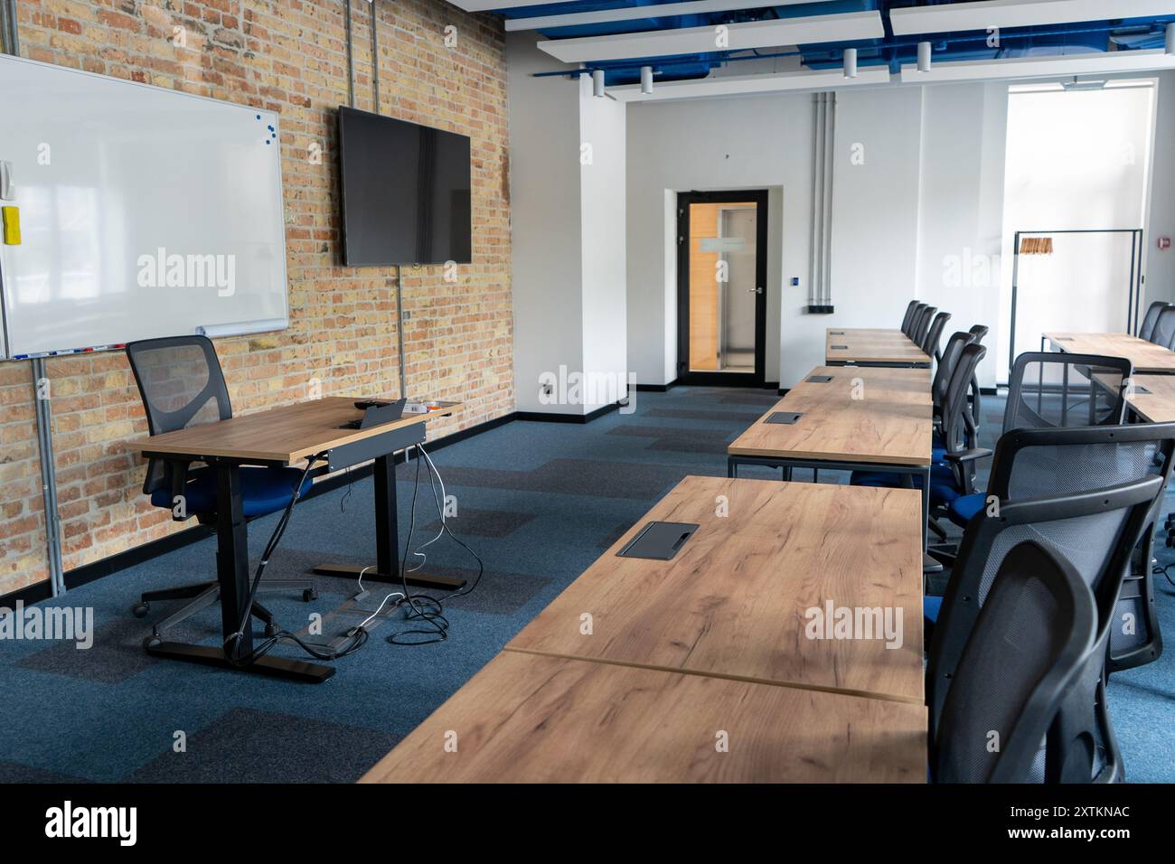 Blackboard, screen and teacher's desk. Empty room with tables and ...