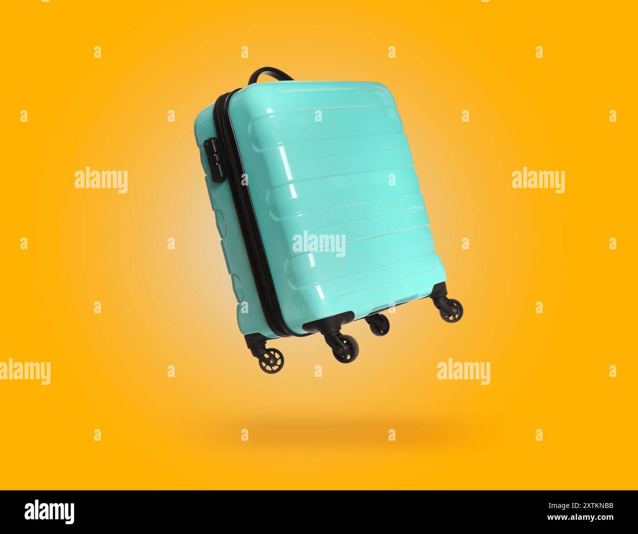 Turquoise suitcase in air on orange background Stock Photo - Alamy