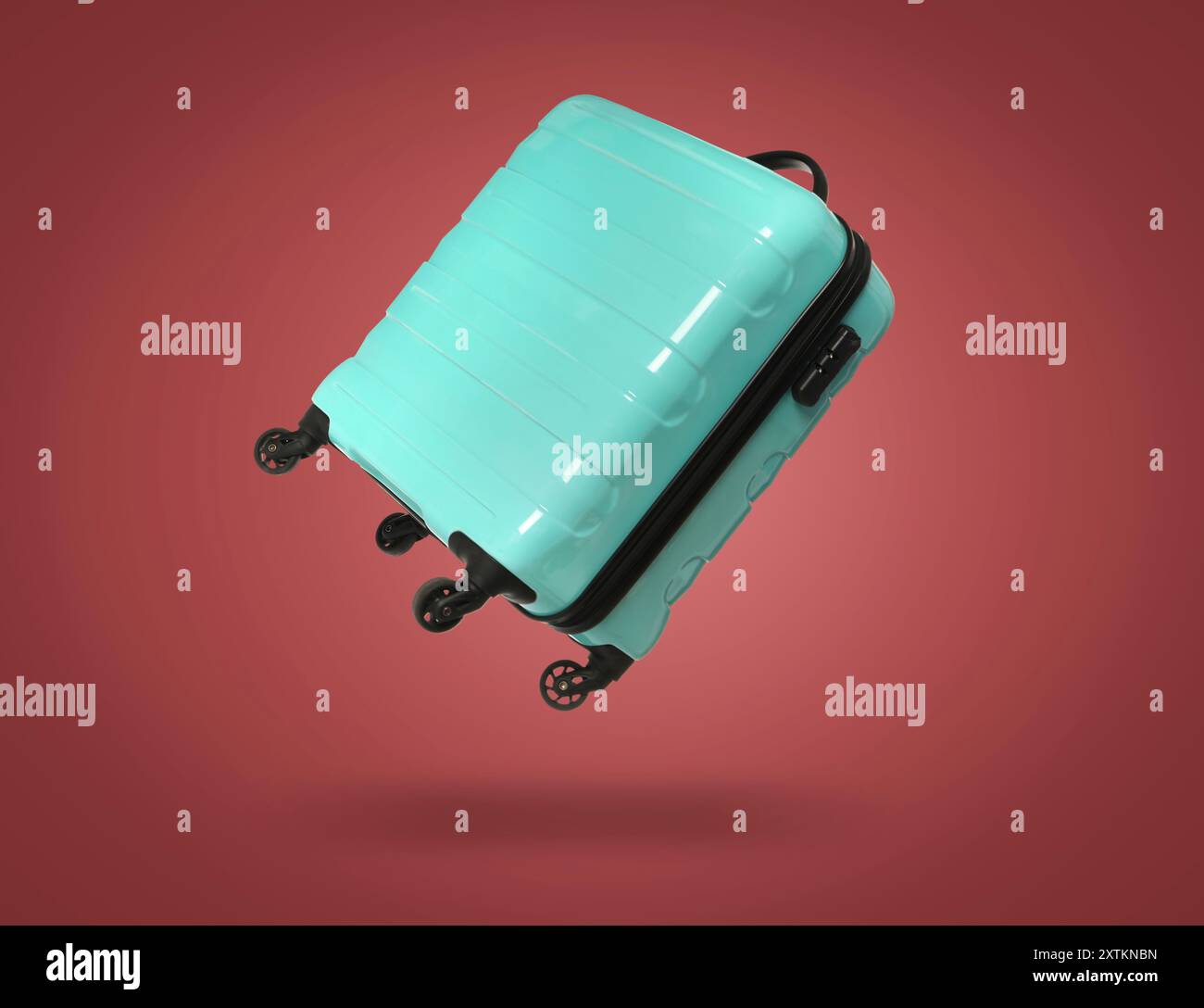 Turquoise suitcase in air on burgundy background Stock Photo - Alamy