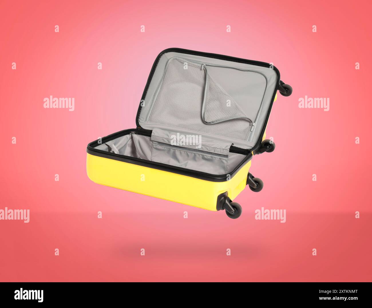 Open empty suitcase in air on coral background Stock Photo - Alamy