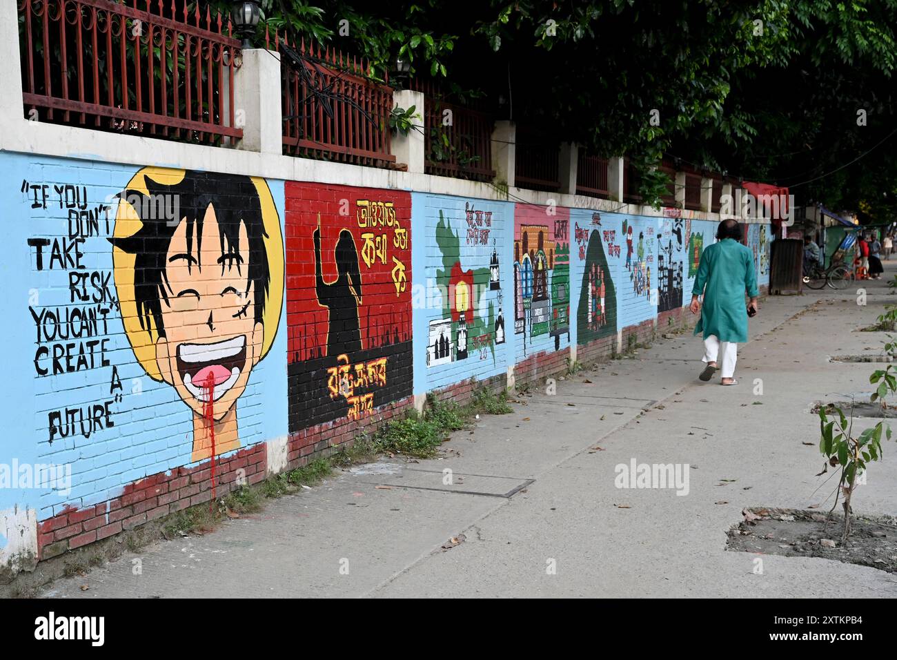 People are walking past a graffiti wall while students are painting ...