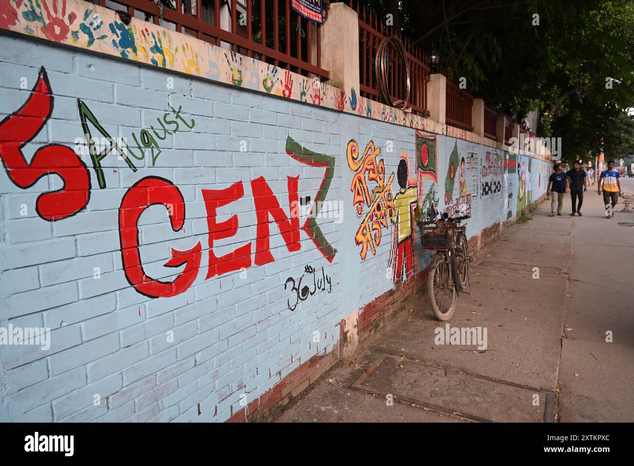 People are walking past a graffiti wall while students are painting ...