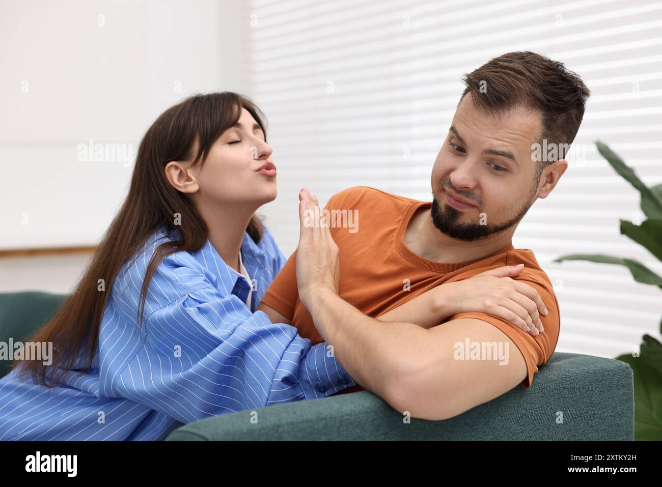 Embarrassed man refusing from woman's kiss at home Stock Photo - Alamy