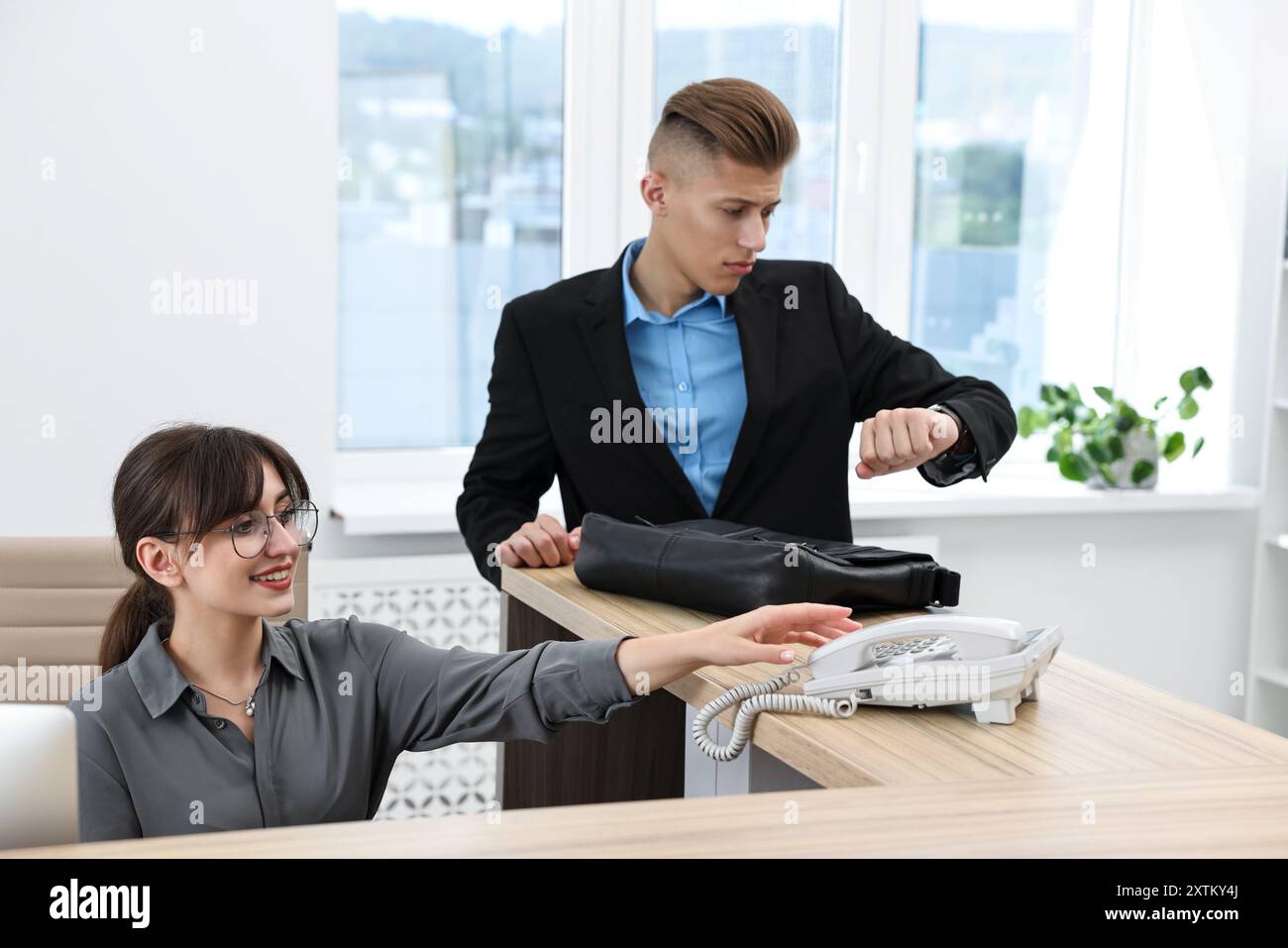 Professional receptionist working with client in office Stock Photo - Alamy