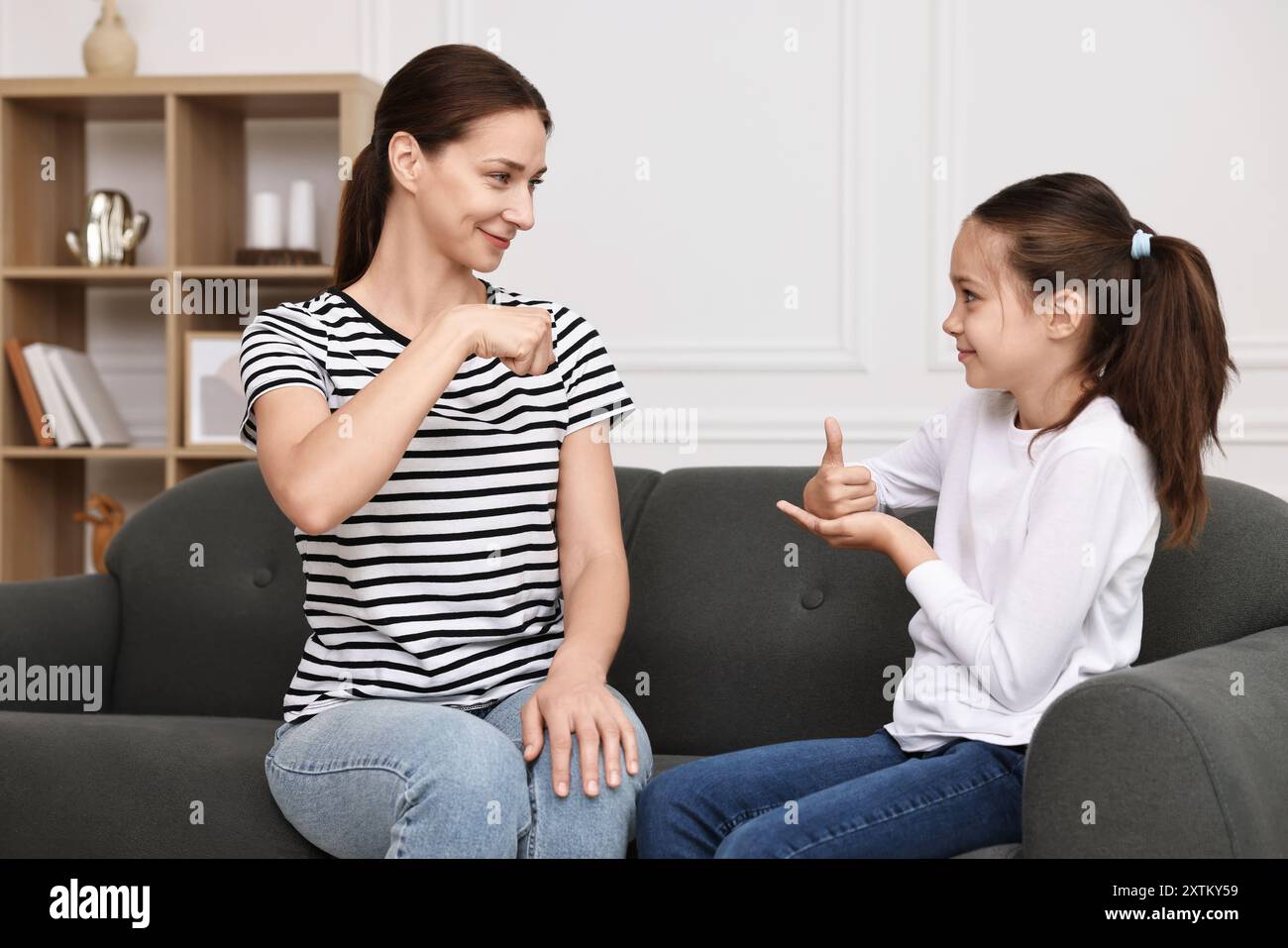 Woman and her daughter using sign language for communication at home ...