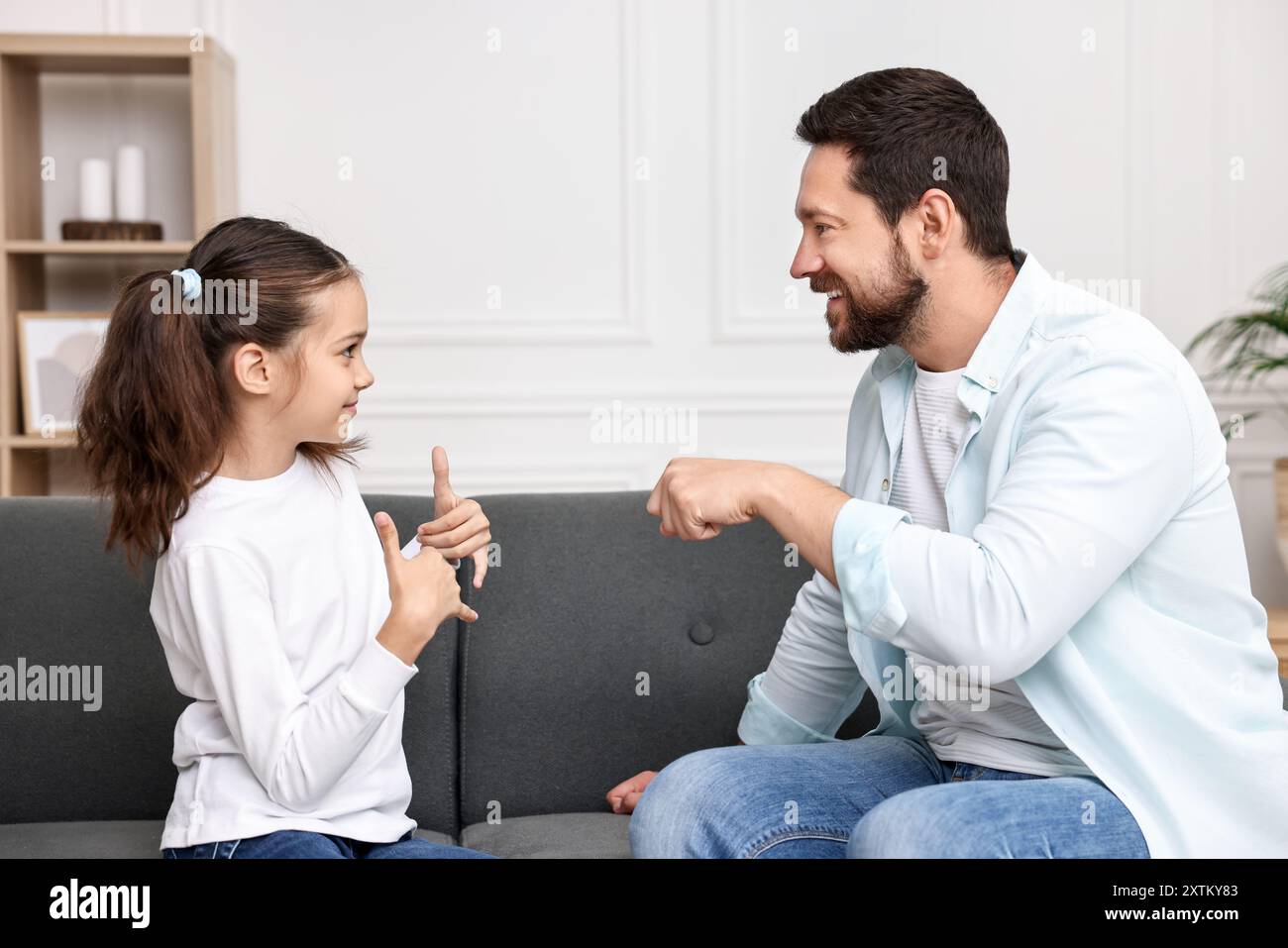 Man and his daughter using sign language for communication at home ...