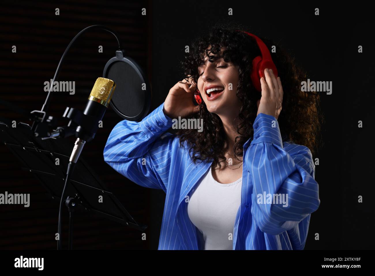 Vocalist with headphones singing into microphone in professional record ...