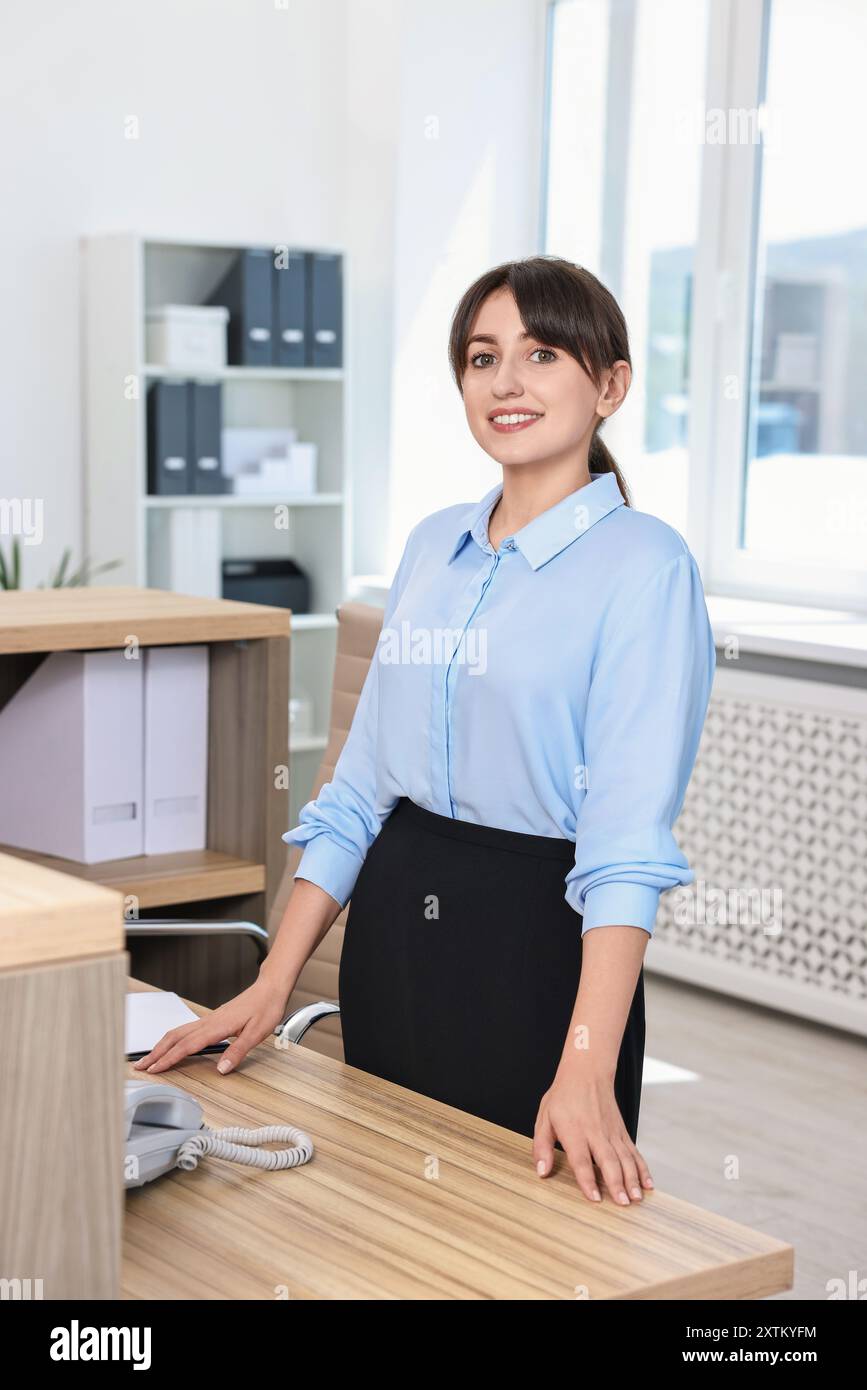 Portrait of receptionist at wooden desk in office Stock Photo - Alamy