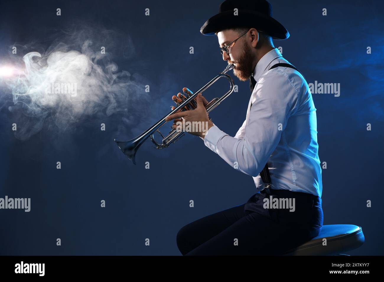 Professional musician playing trumpet on dark background with smoke ...