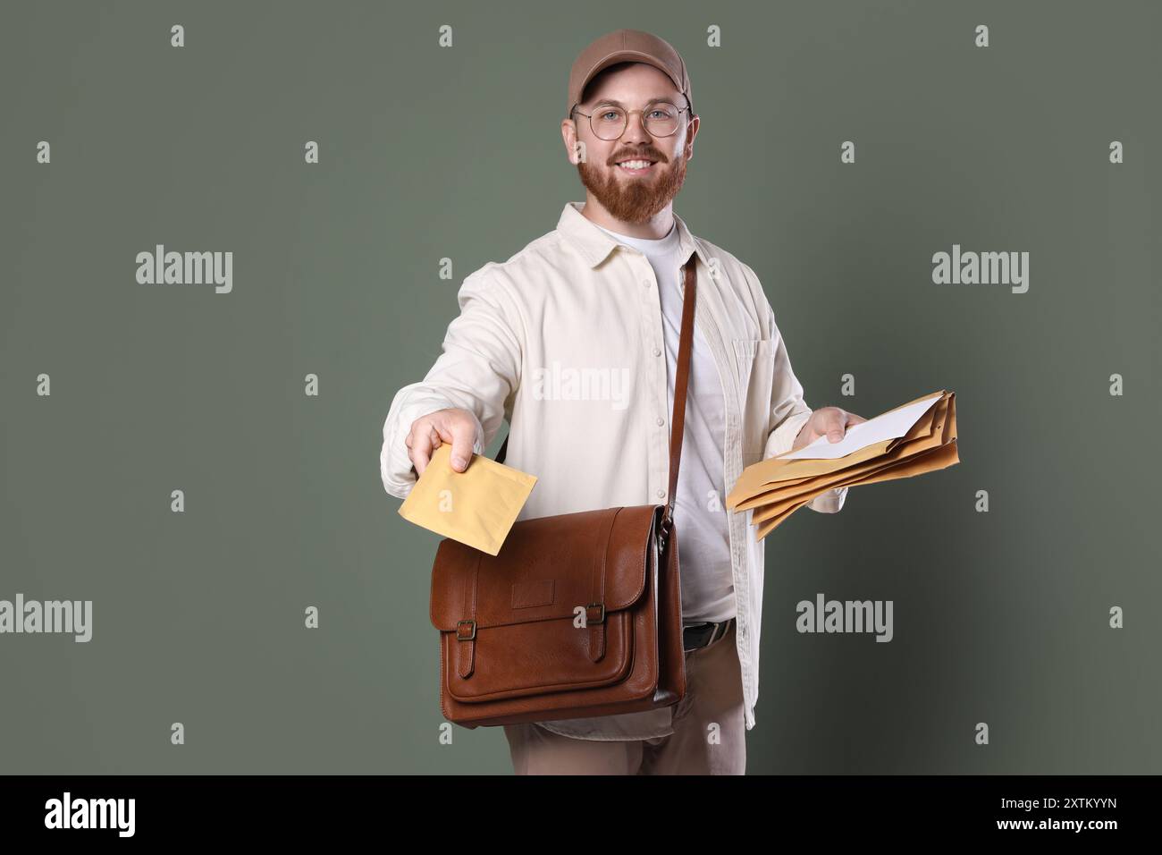 Happy young postman with brown bag delivering letters on olive ...