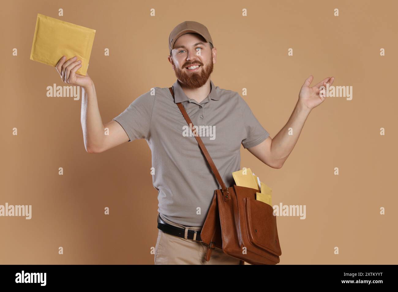 Happy young postman with leather bag delivering letters on brown ...