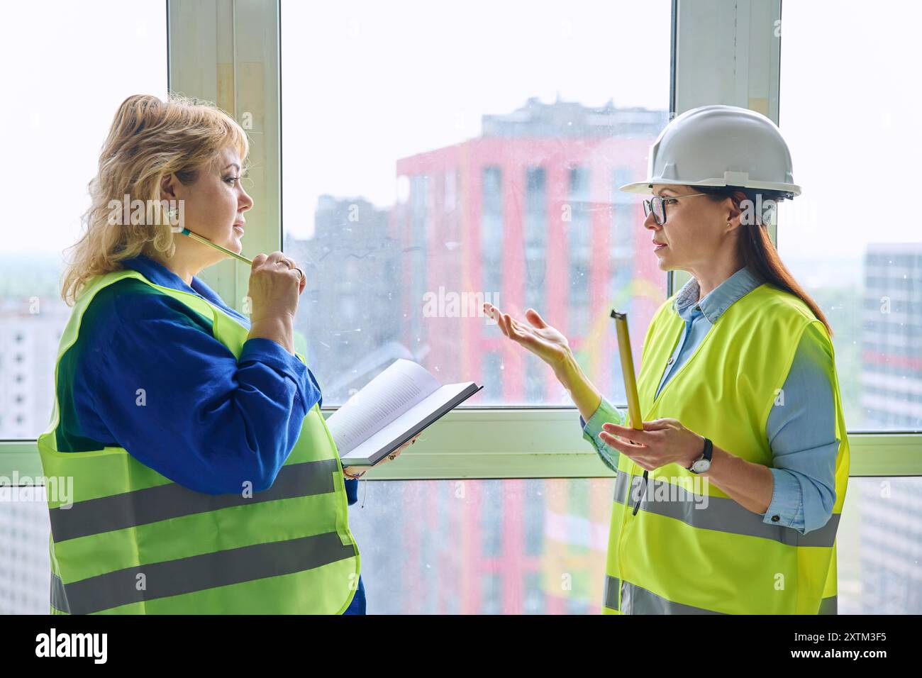 Two female industrial workers taking measurements of windows for ...