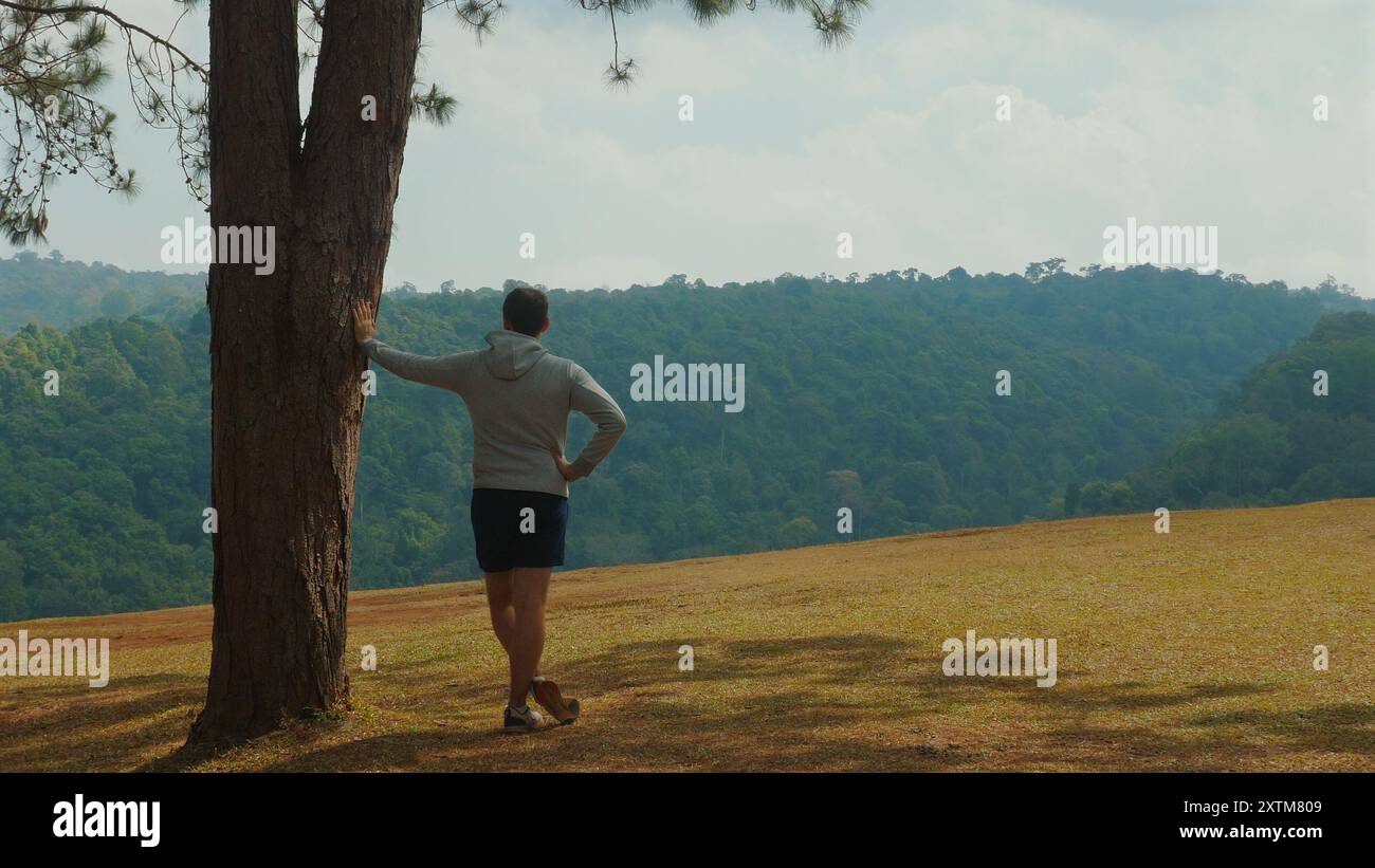 Man Relaxing in Nature, Leaning Against Tree While Admiring Serene ...