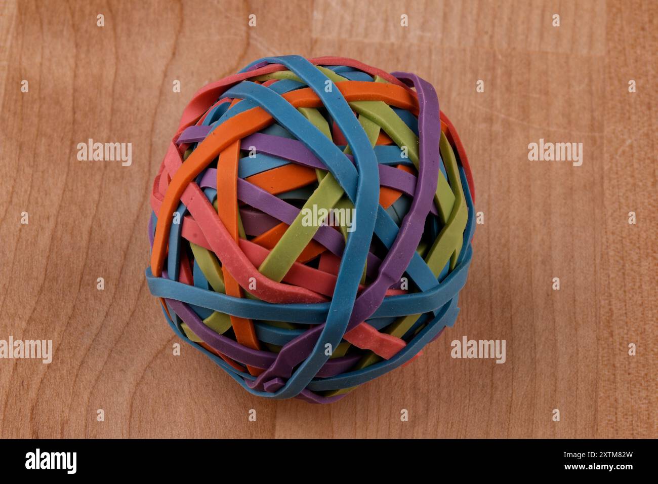 A colorful rubber band ball lies on a table with wooden structures ...