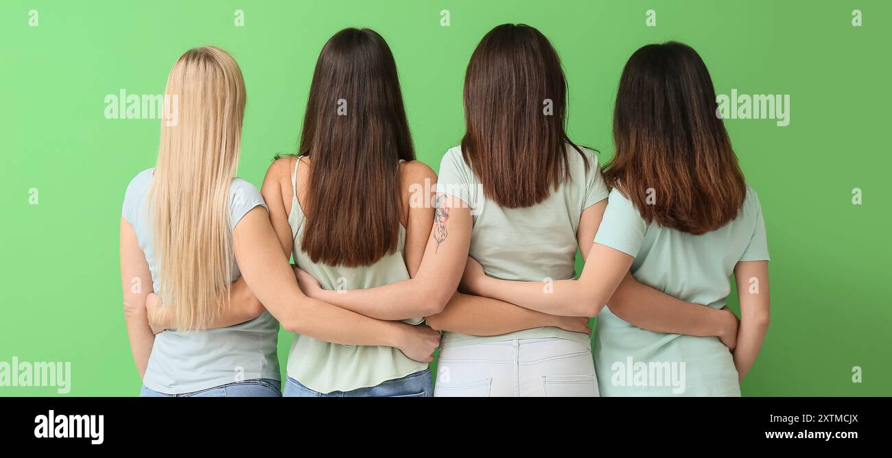 Beautiful hugging women on green background, back view Stock Photo - Alamy