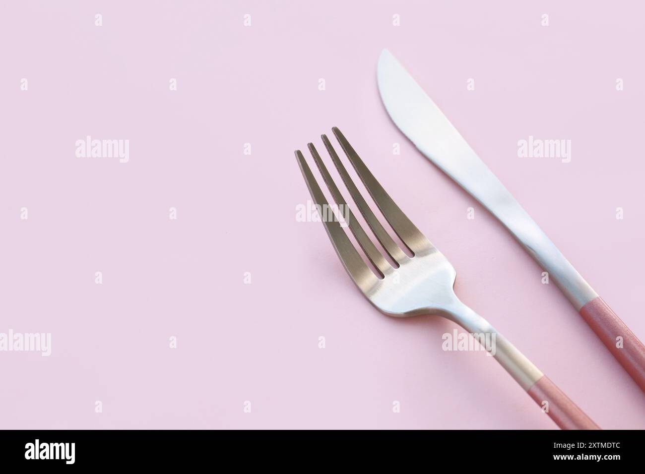 Stainless steel fork and knife on pink background Stock Photo - Alamy