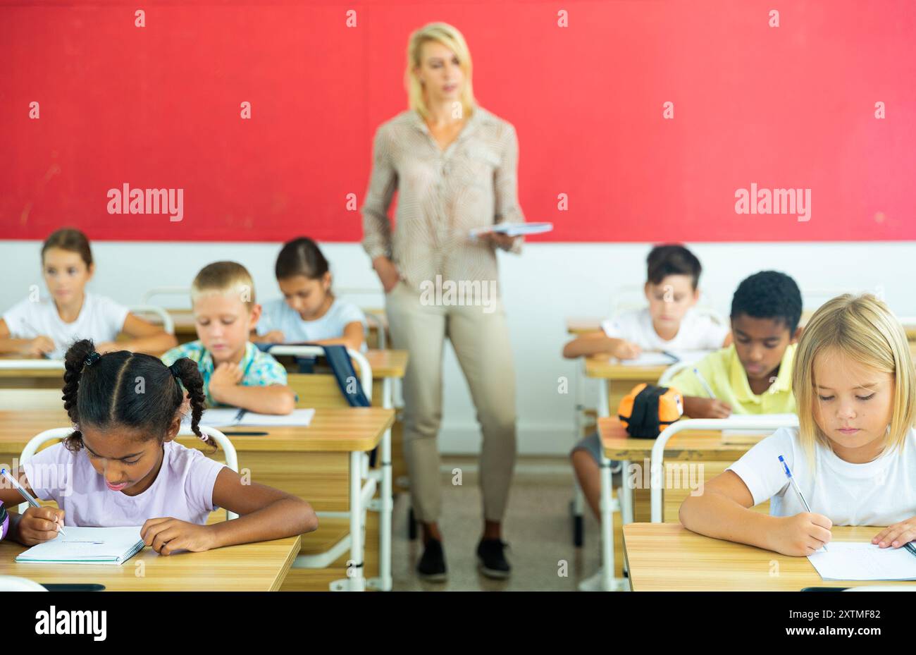 Diligent tweens studying in classroom with female teacher Stock Photo ...
