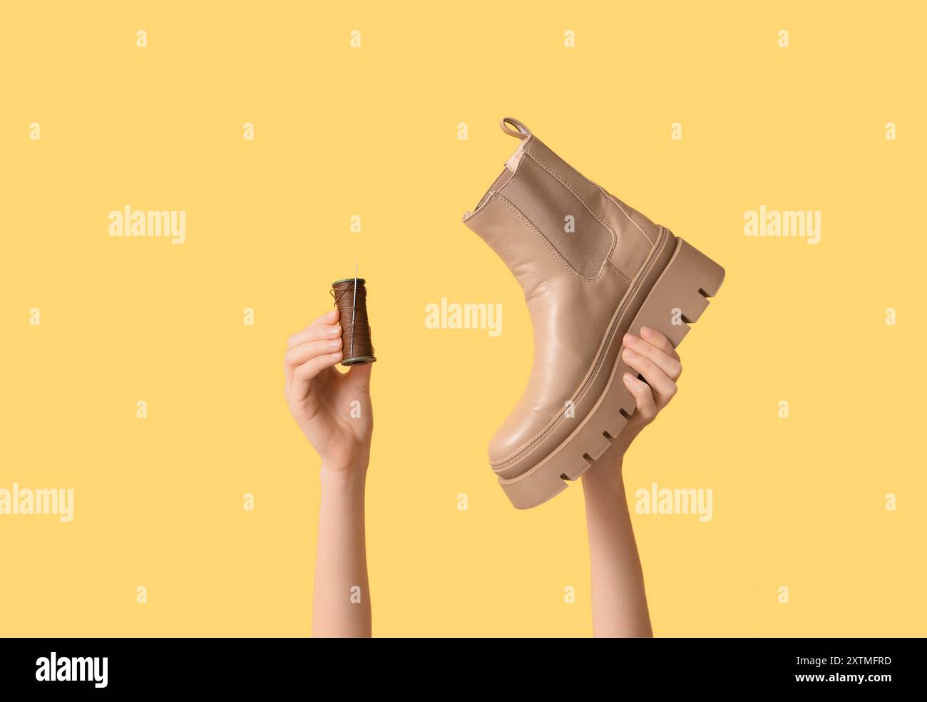 Female hands with boot and sewing thread on yellow background. Shoes ...