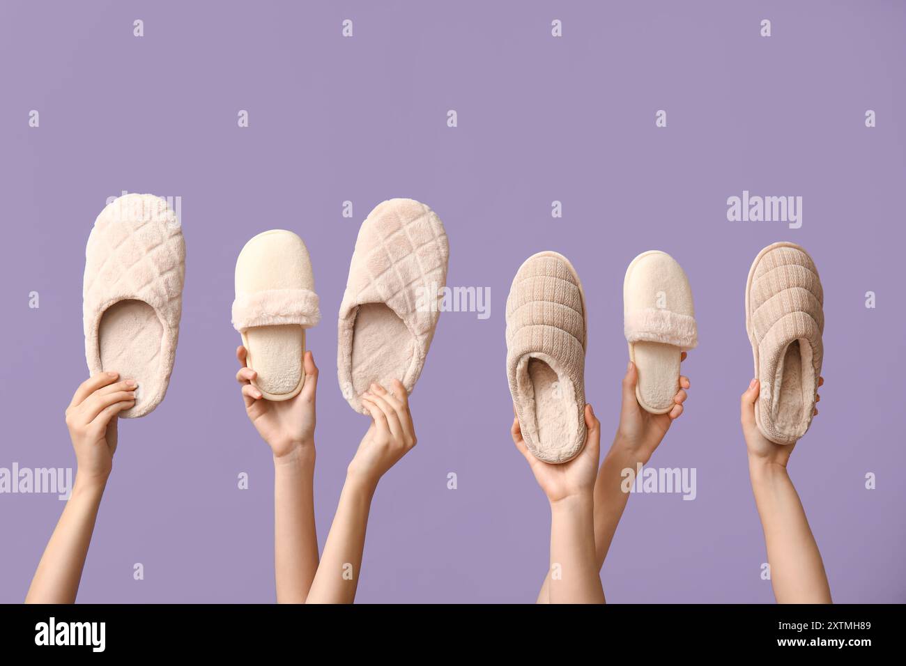 Female hands holding different slippers on lilac background Stock Photo ...