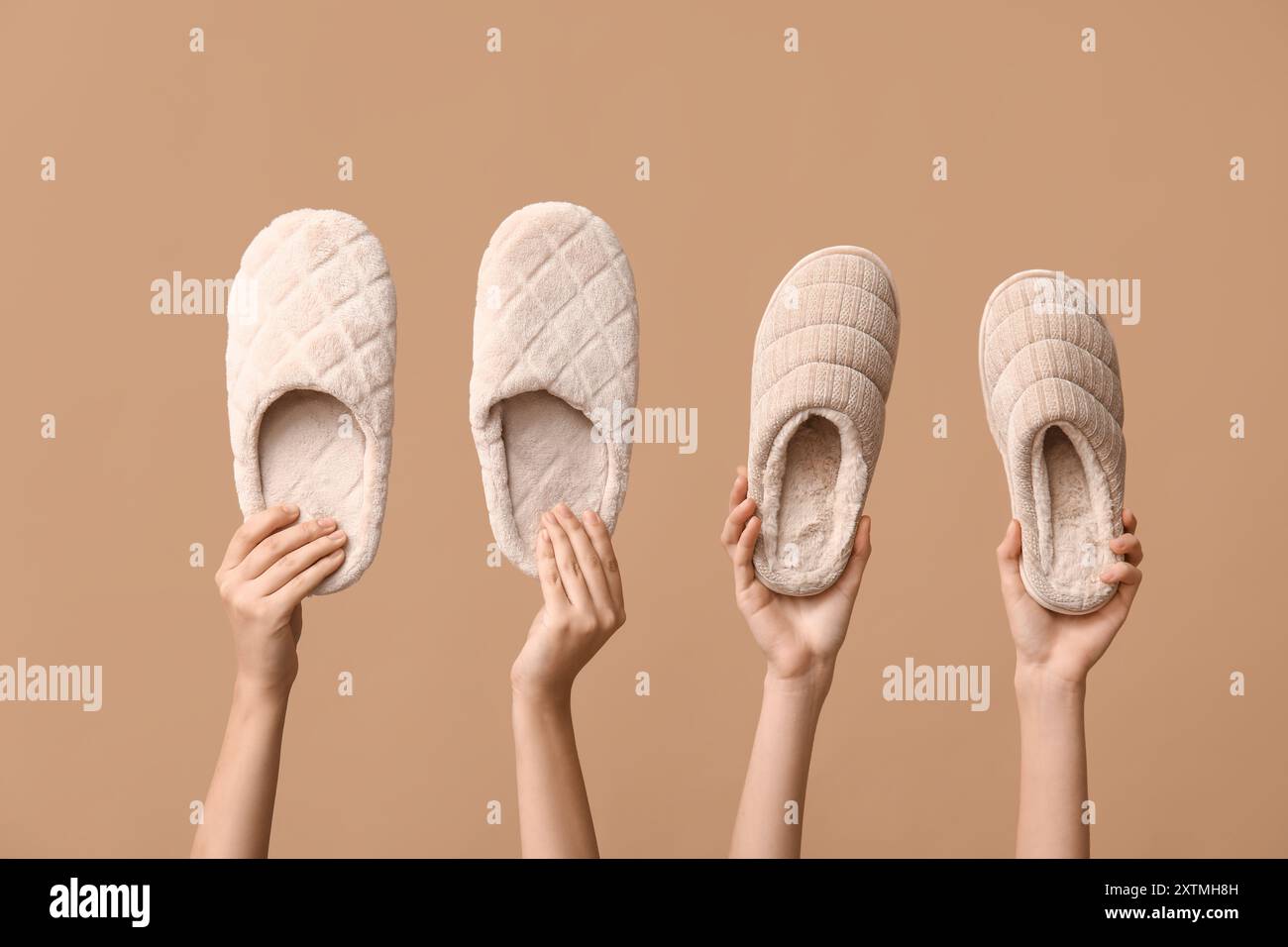 Female hands holding slippers on beige background Stock Photo - Alamy
