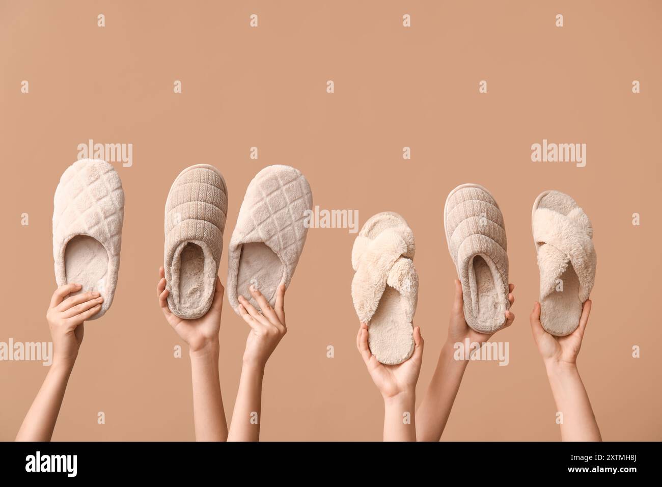 Female hands holding different slippers on beige background Stock Photo ...