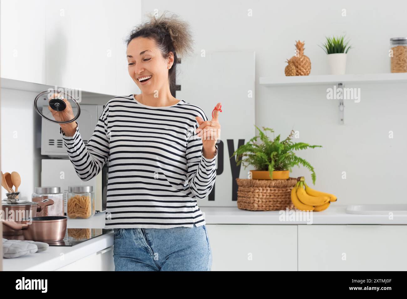 Surprised middle-aged woman with red string on her finger cooking in ...
