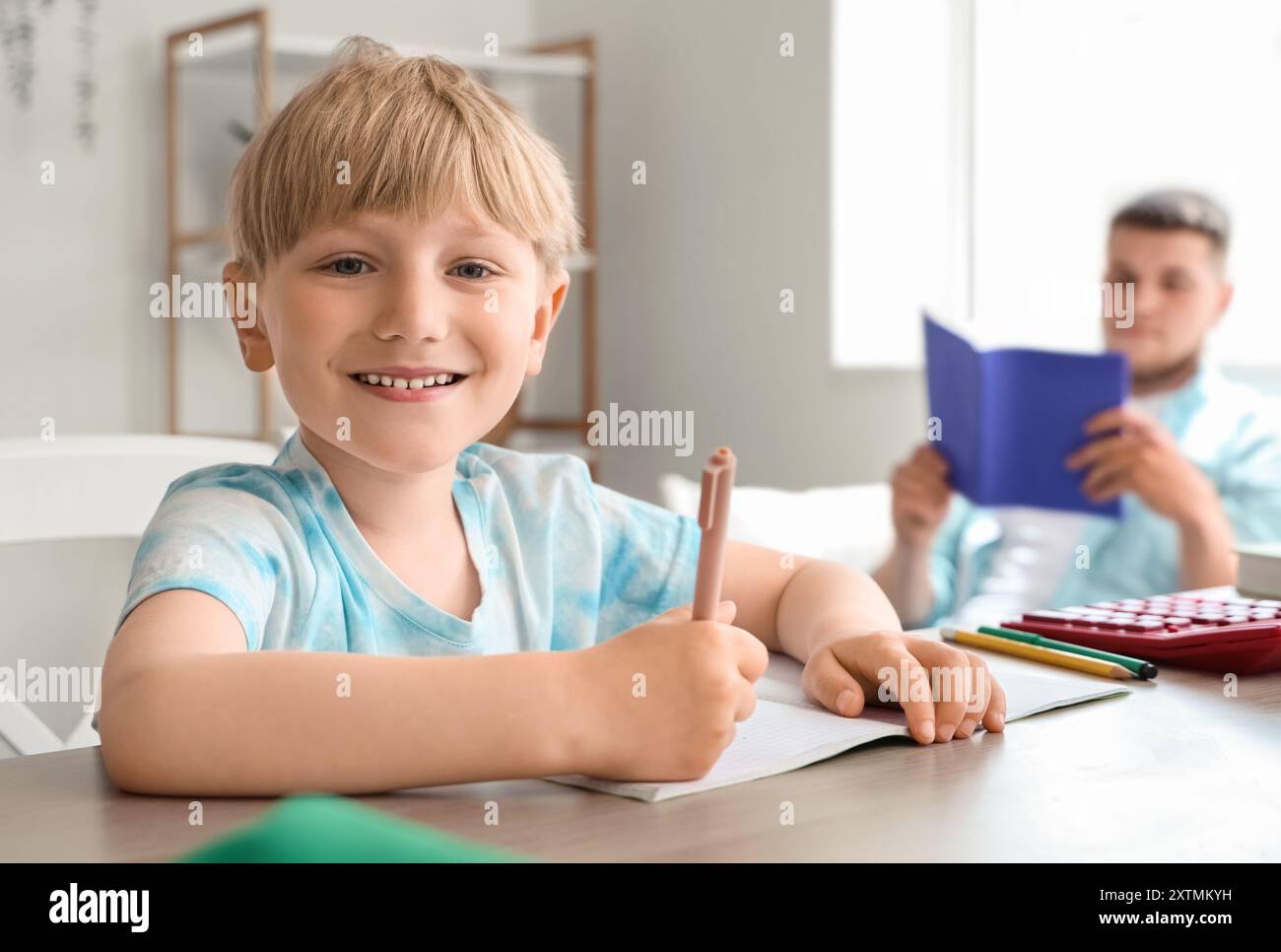 Cute boy taking dictation by his father in room Stock Photo - Alamy
