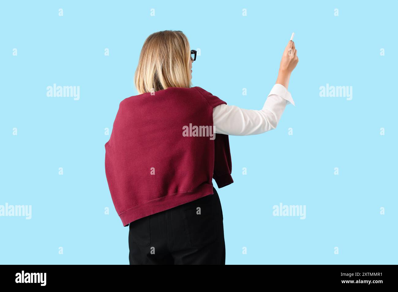 Mature female math teacher holding chalk on blue background Stock Photo ...