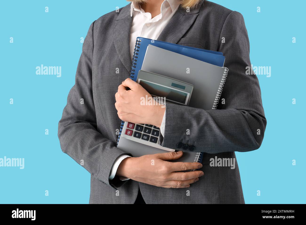 Mature female math teacher with notebooks and calculator on blue ...
