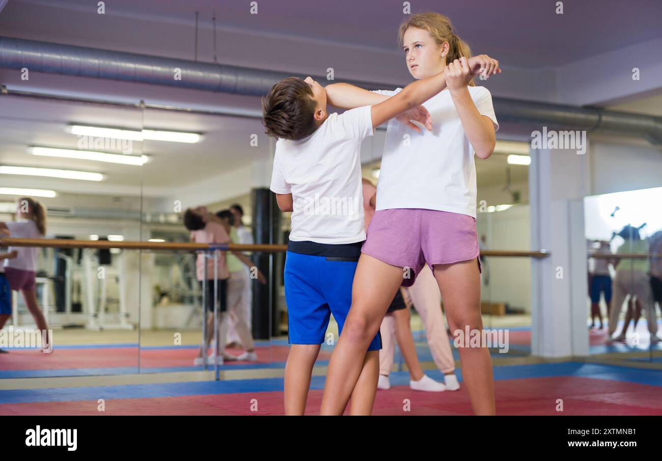 kids in pair exercising self-defense movements during group class with ...
