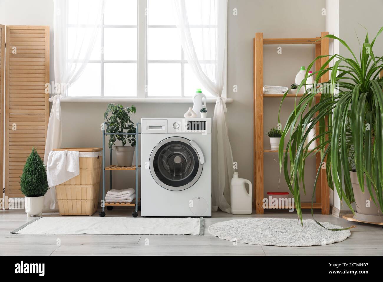 Washing machine, laundry basket and folding screen near window in room ...