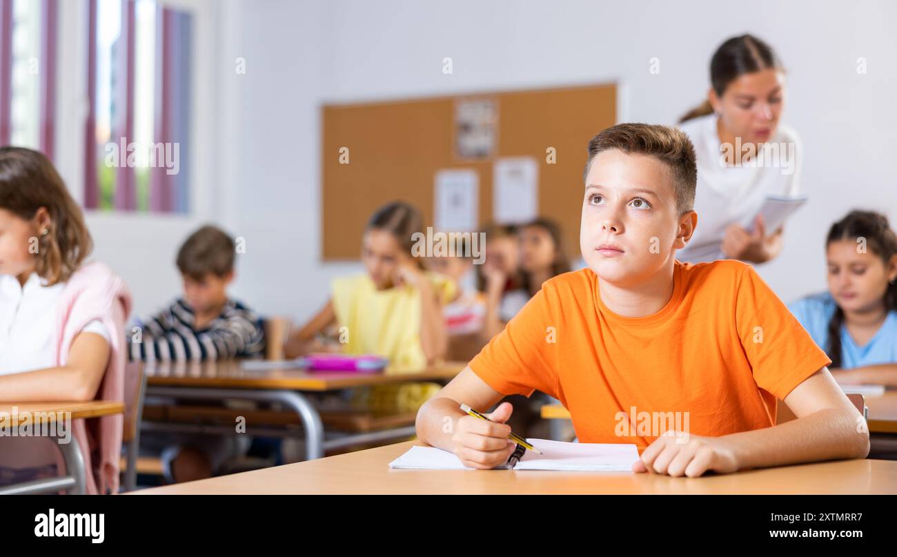 Diligent tween boy making notes of teacher lecture in class Stock Photo ...