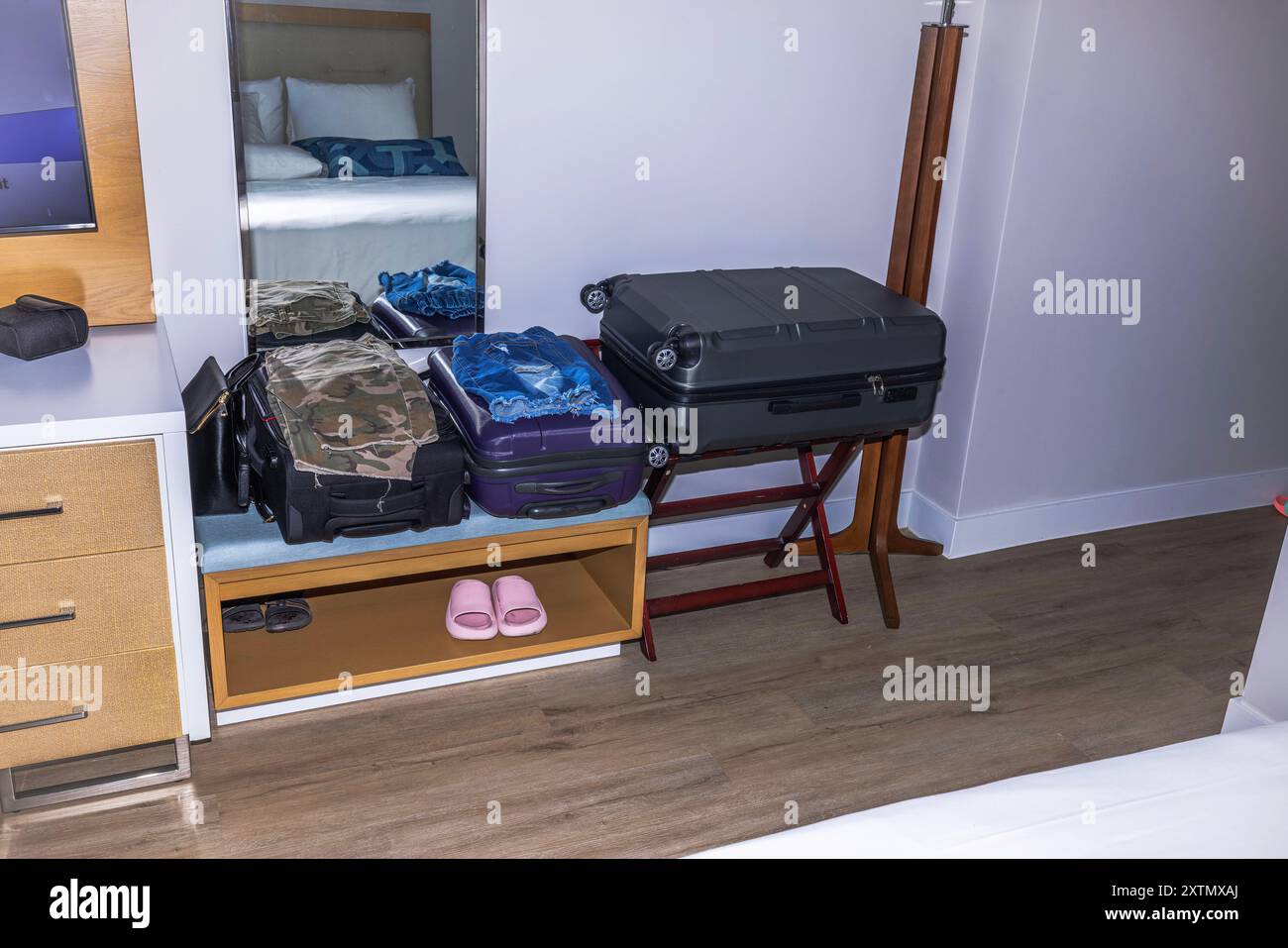 Hotel room with luggage bench and nightstand, suitcases with a few ...