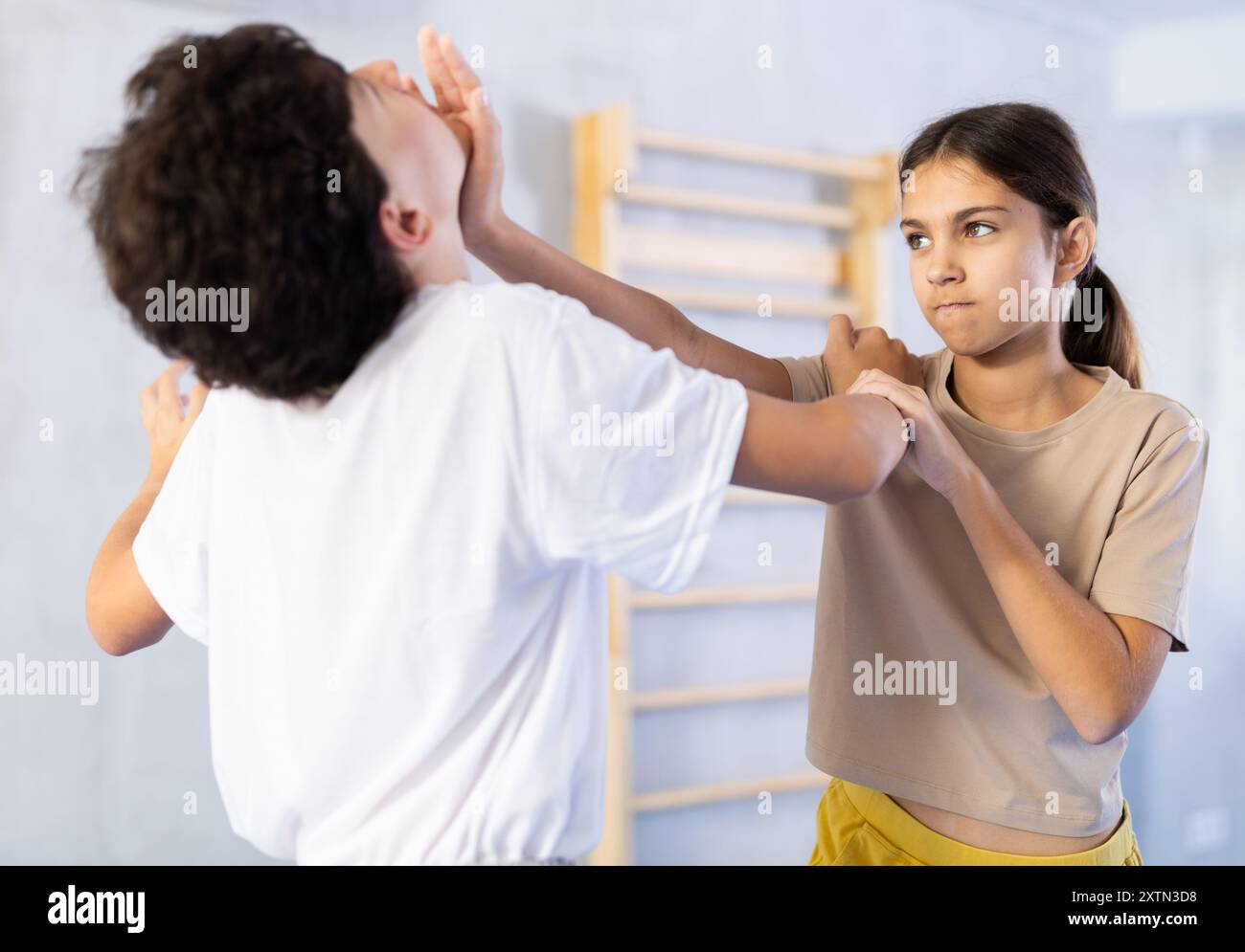 Girls and boys practicing in pair self defence movements with female ...