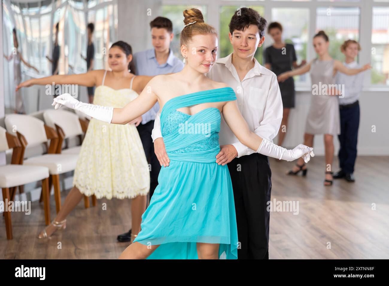 Adolescent ballroom dancers practicing elegant dance moves in pairs ...