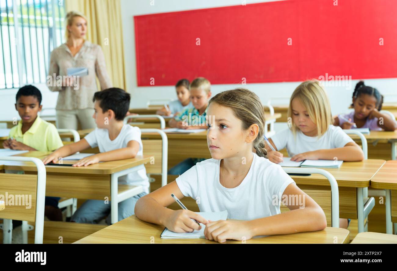 Diligent tween girl studying with classmates in elementary school Stock ...