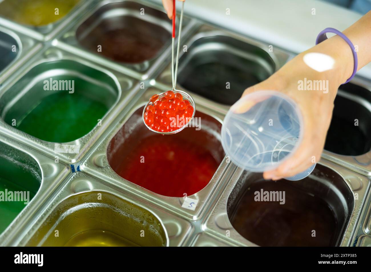 Making bubble tea in cafe. Metal containers with colorful tapioca balls ...