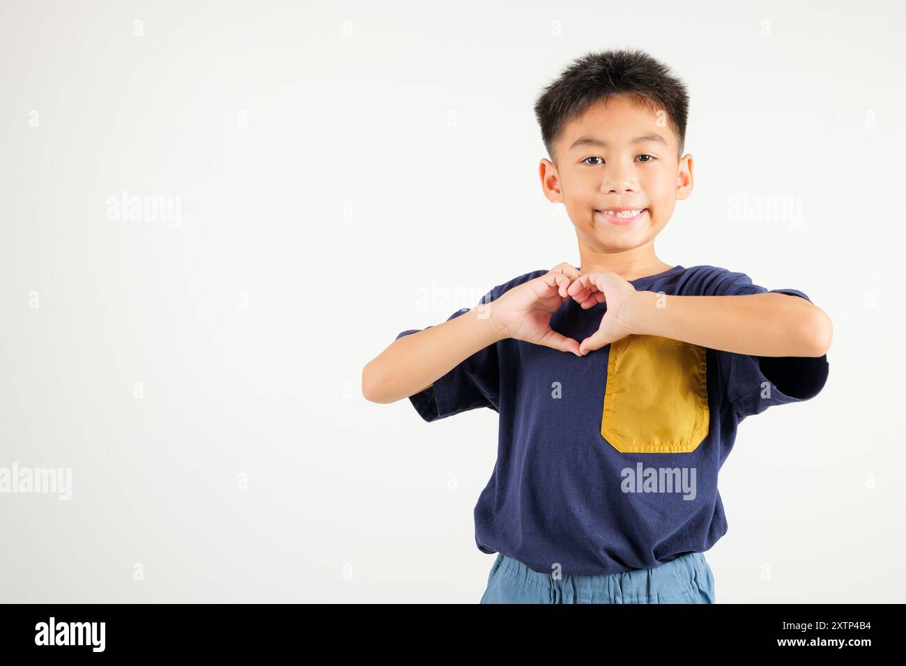A smiling Asian young kid boy shows confidence, creating a heart shape ...