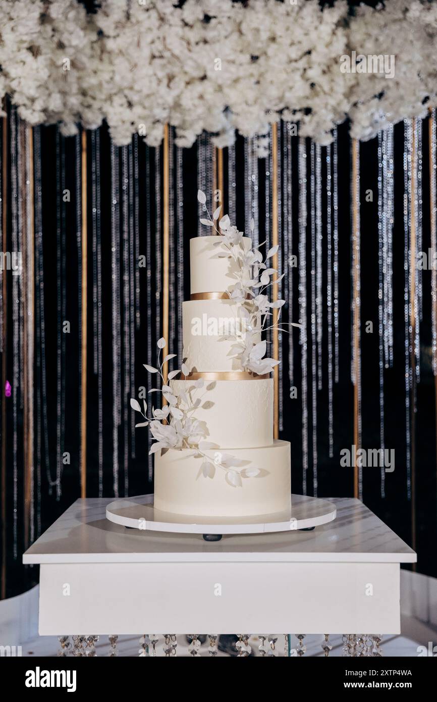 Wedding setup with three-tier white cake with floral accents. Wedding ...