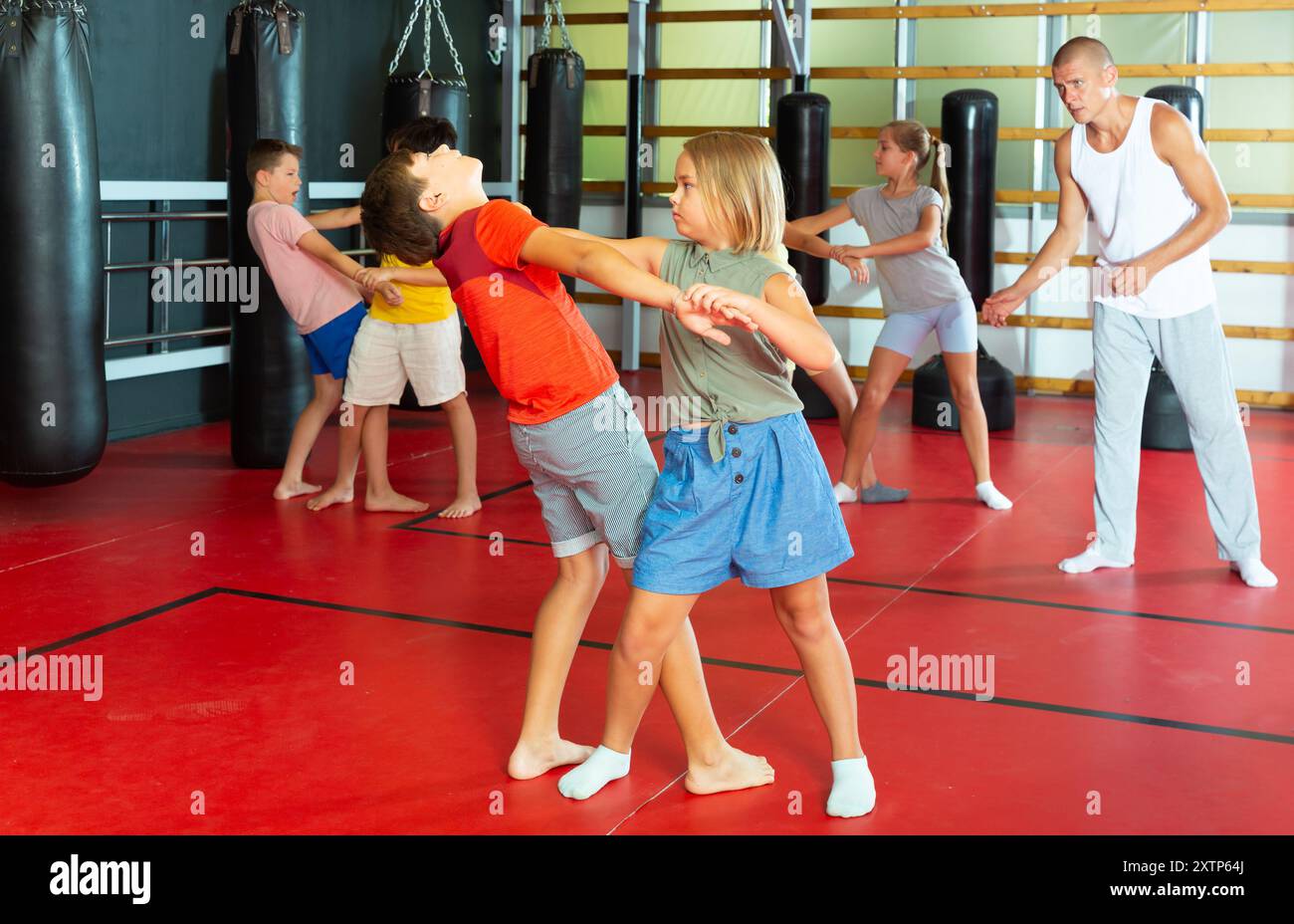 Preteen children practicing in pair self-defence movements with male ...