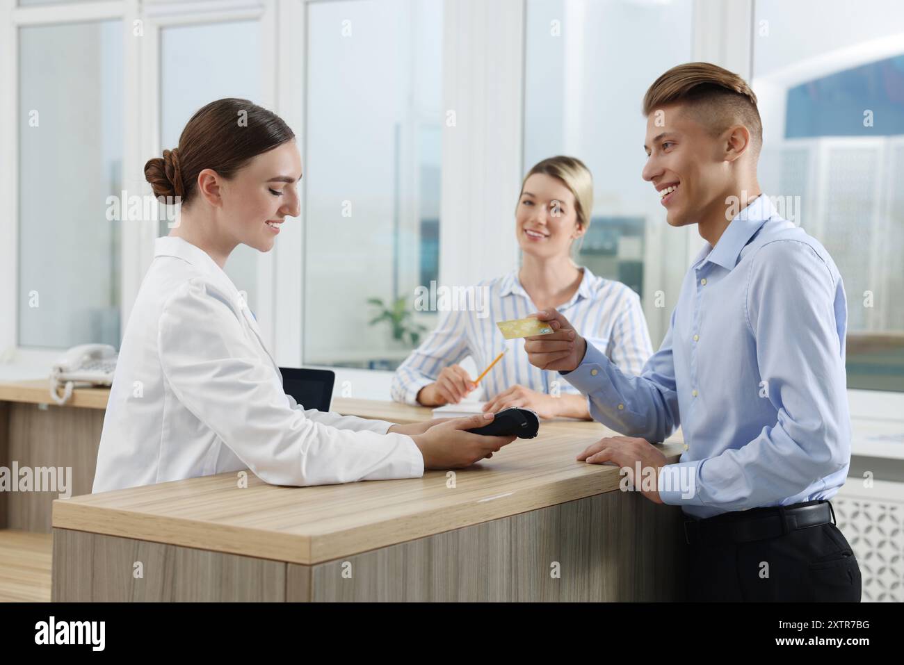 Receptionist taking payment from client via terminal at hospital Stock ...