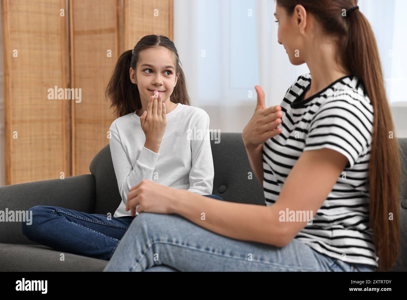 Woman and her daughter using sign language for communication at home ...