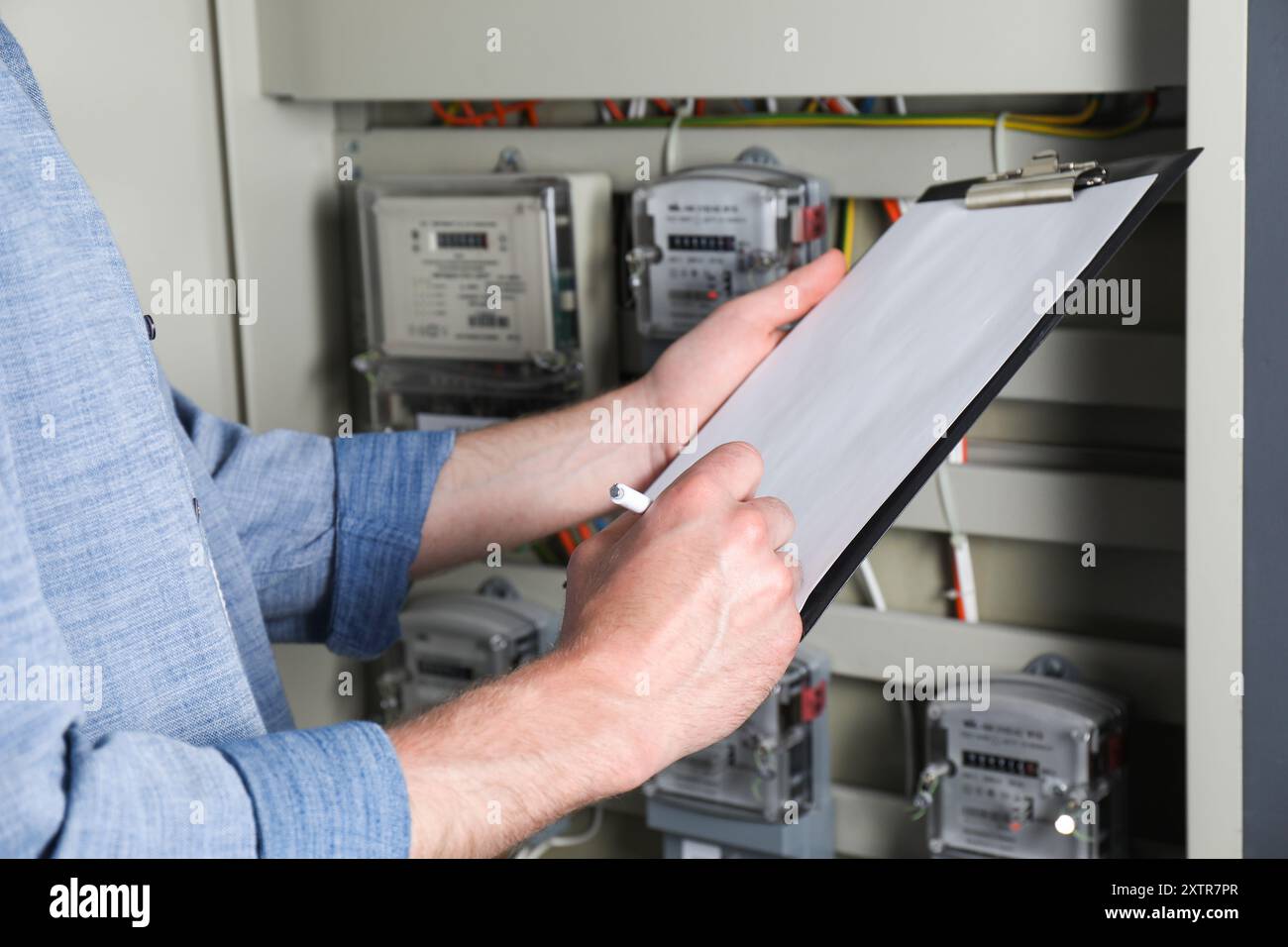 Technician worker with clipboard inspecting electricity meter, closeup ...